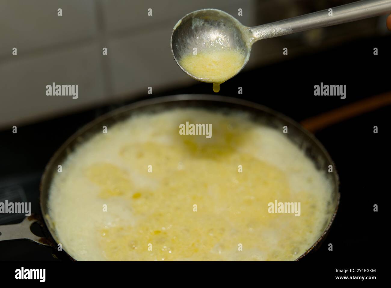 Spoon dripping melted golden ghee into a hot pan, ready for cooking ...