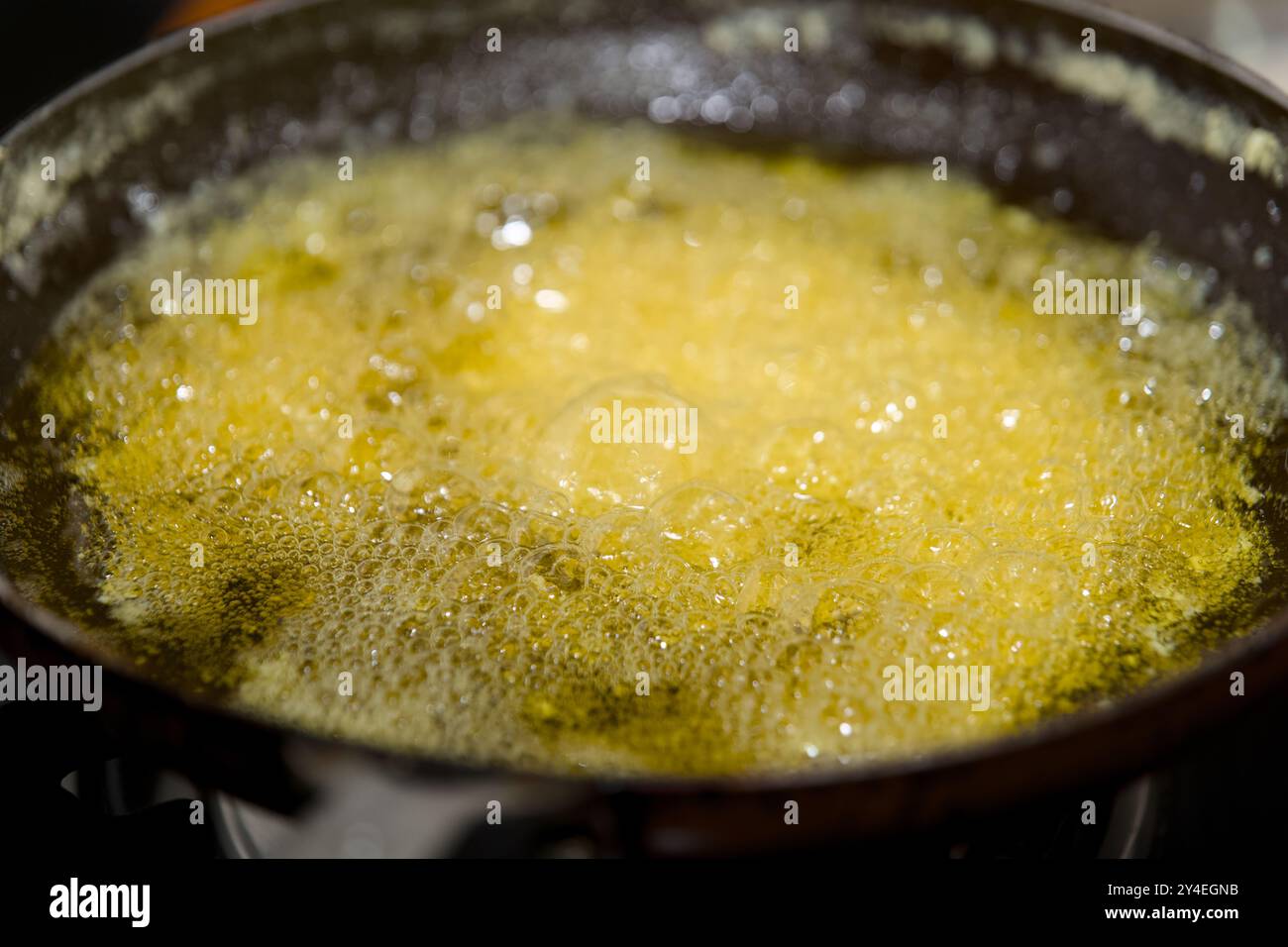 Hot, bubbling golden Ghee in a pan, ready for frying and cooking ...