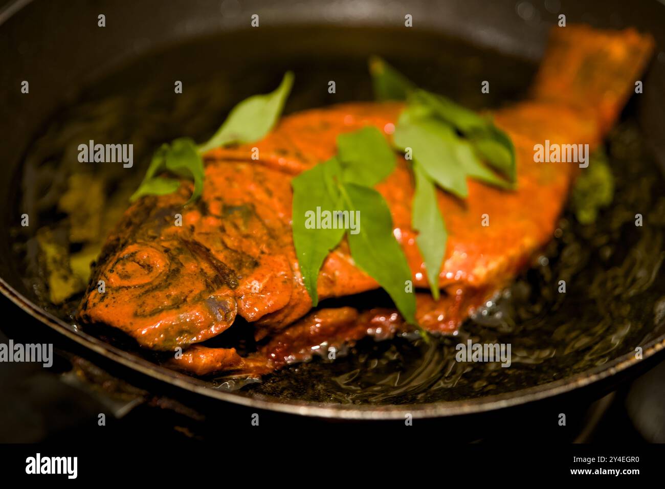 A whole fish, coated in vibrant spices, sizzles enticingly in hot oil ...