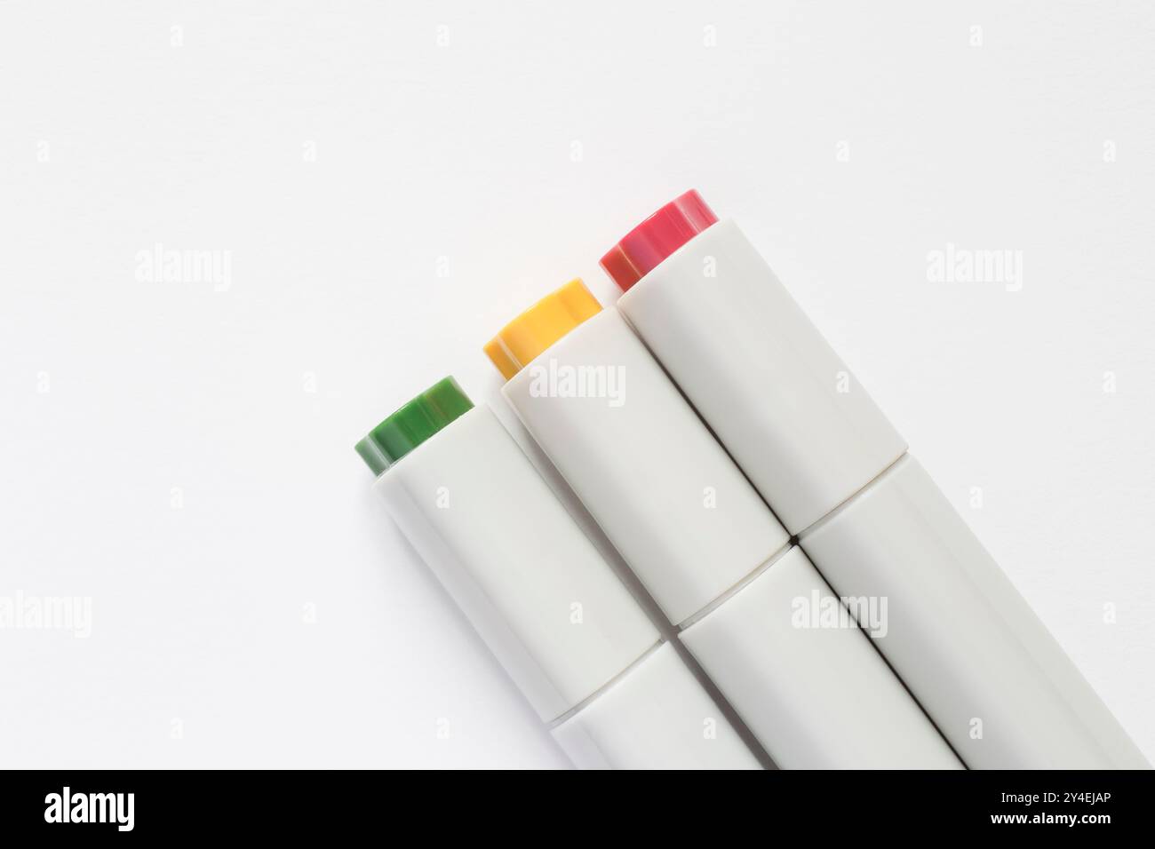 close up of three closed markers lying on white page of sketch book ...