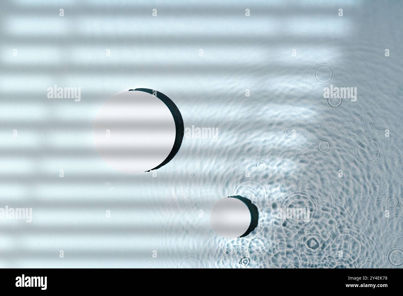 Raindrops create ripples on water surface with shadows from window ...