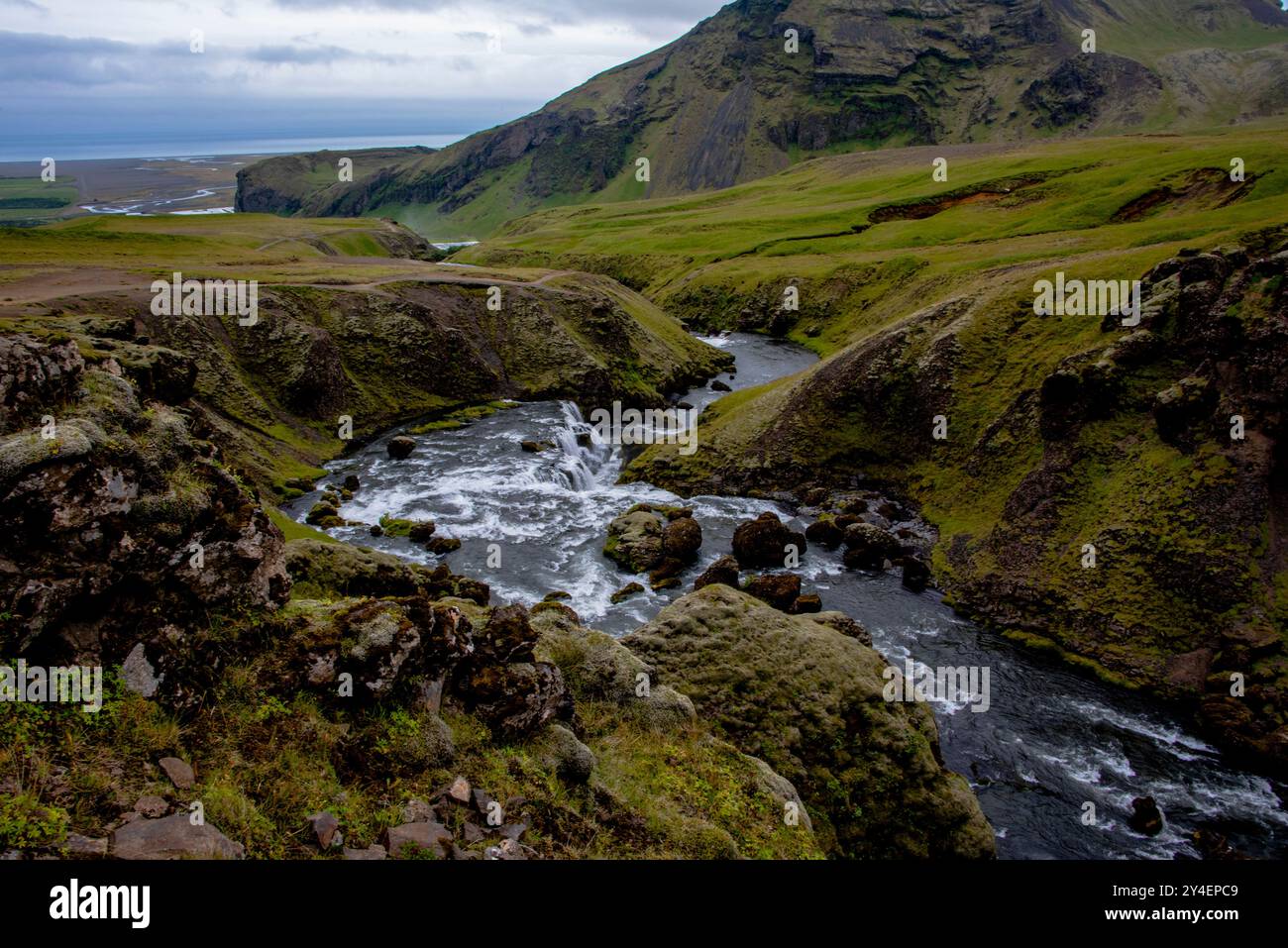 the Skogafoss waterfalls in summer with the green of the mountains and ...