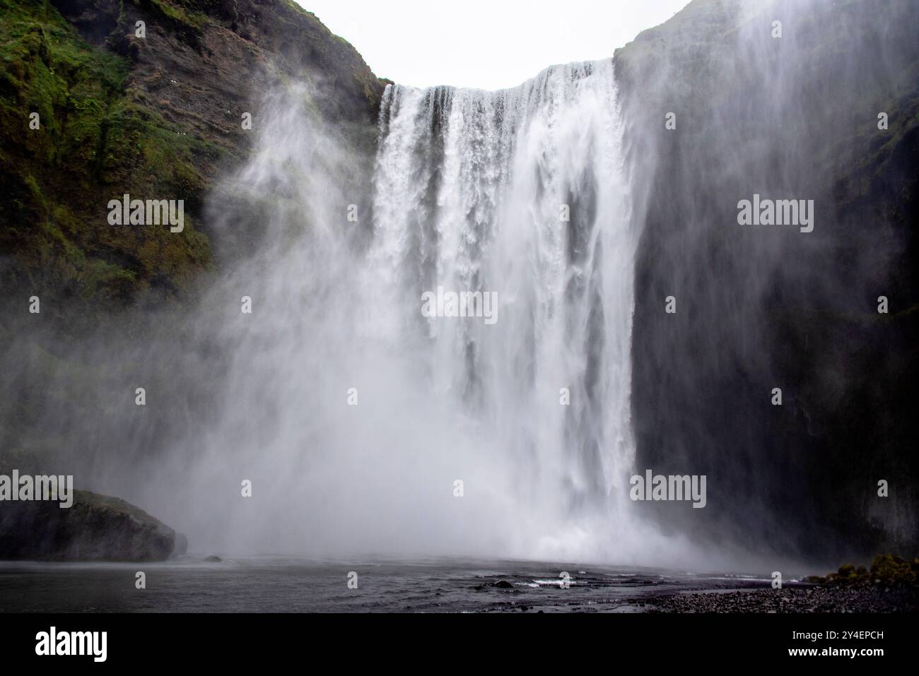 the Skogafoss waterfalls in summer with the green of the mountains and ...