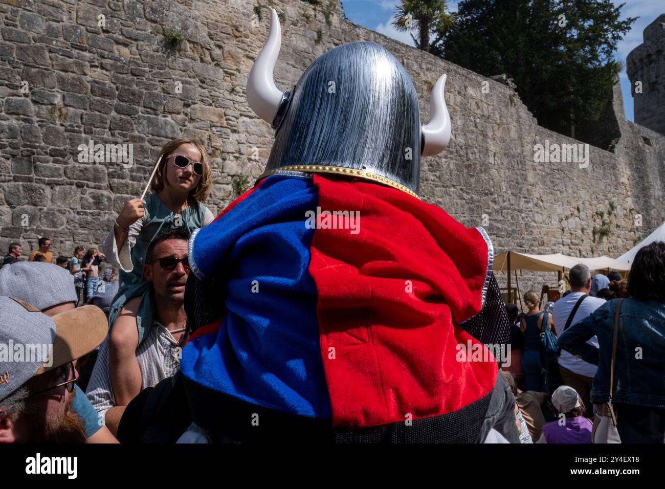 A child boy dressed as a knight rides on his parent's shoulders at the ...