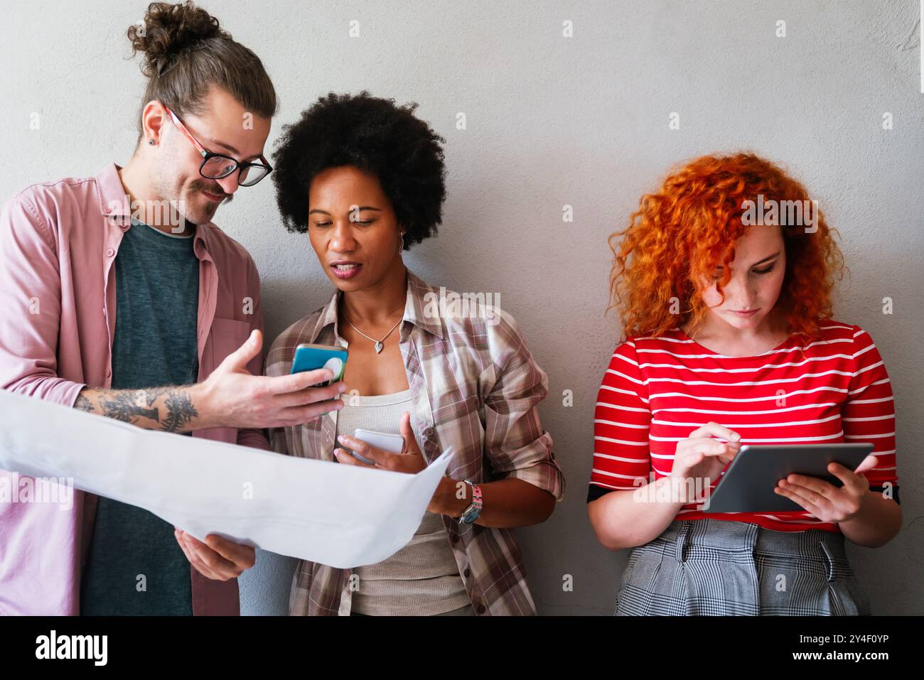 Engineers helping design work on blueprints, collaborate on structural ...