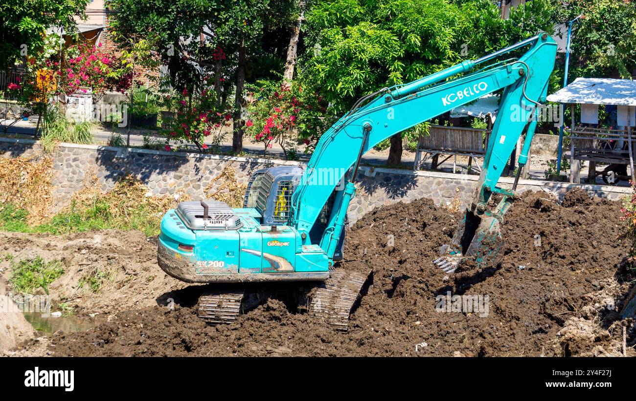 Excavator driver is digging soil in the river to make the water flow ...