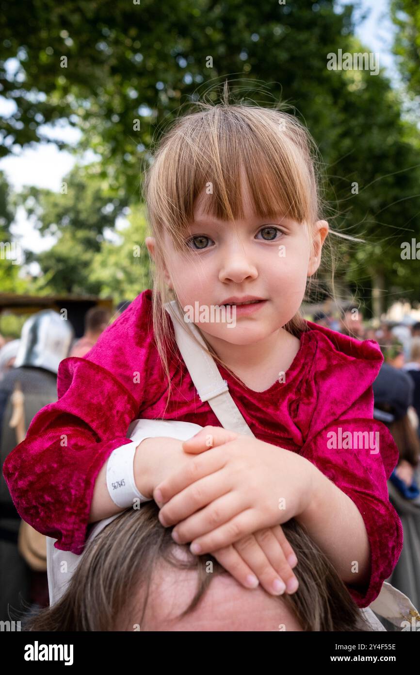 A child girl in medieval dress on her parent's shoulders at the Fete ...
