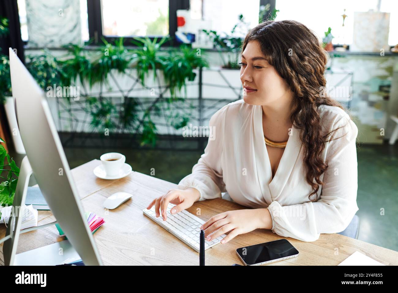 A vibrant young woman engages with her computer at office, immersed in ...