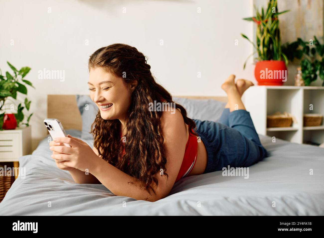 A joyful plus size woman lounges comfortably on her bed, deeply engaged ...