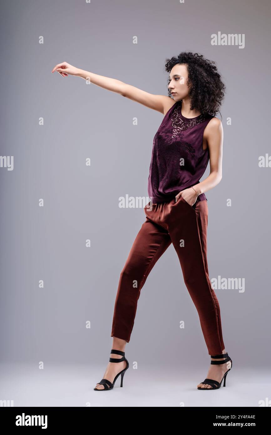 Fashion model is posing with her right hand outstretched and her left ...