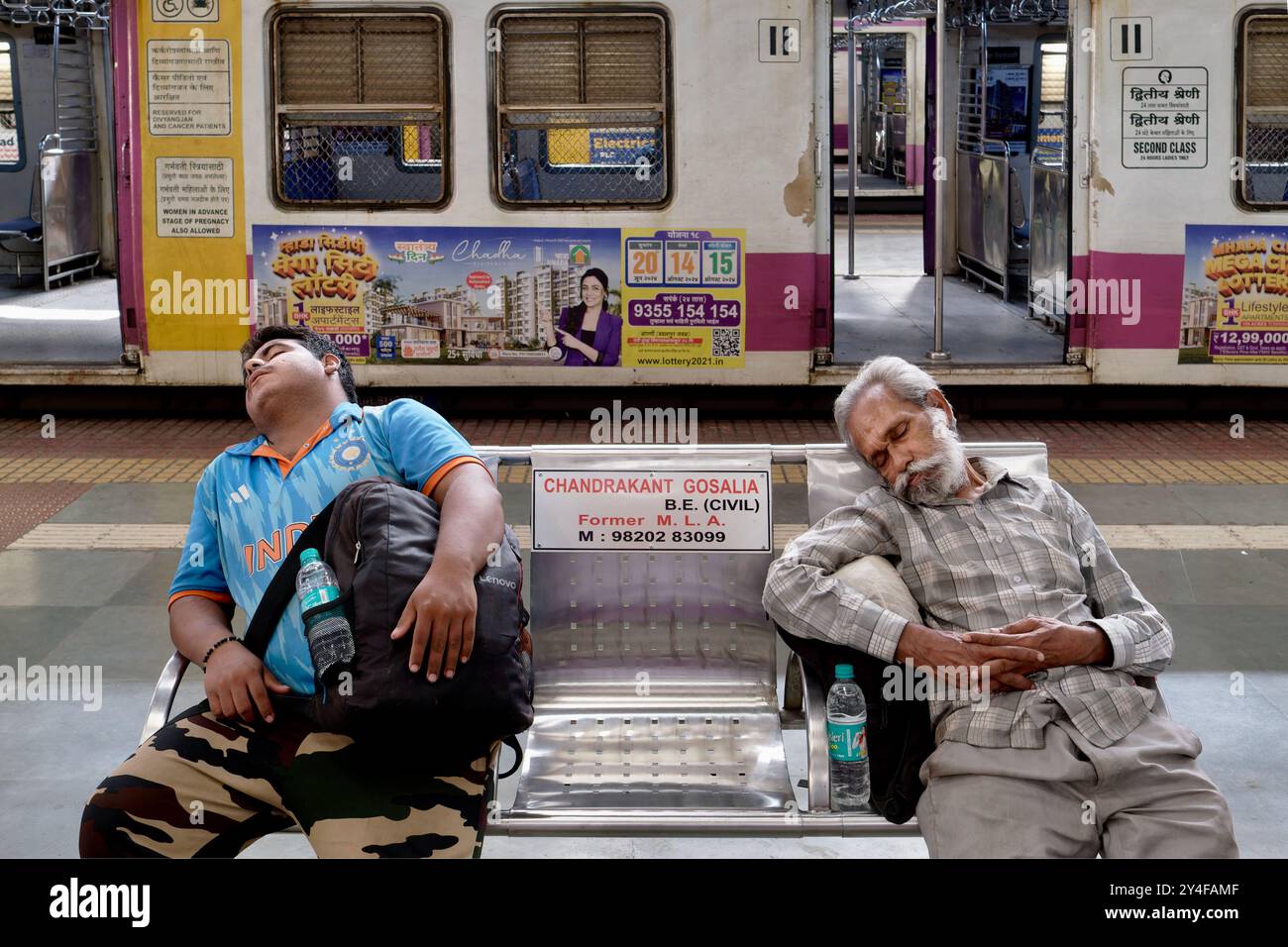 Two male passengers sleep on an bench on a railway platform at ...