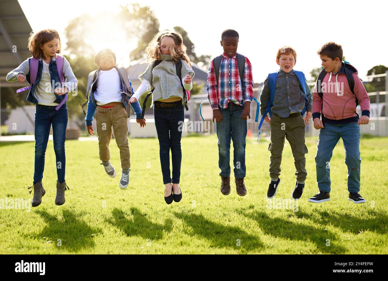 School kids, jumping and playing outdoor on grass with backpack for ...
