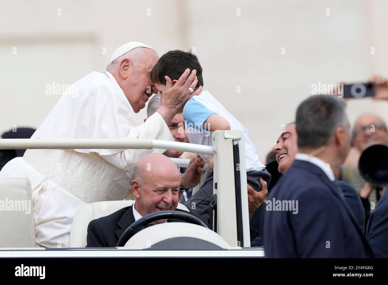 Pope Francis kisses a child as he leaves at the end of his weekly ...