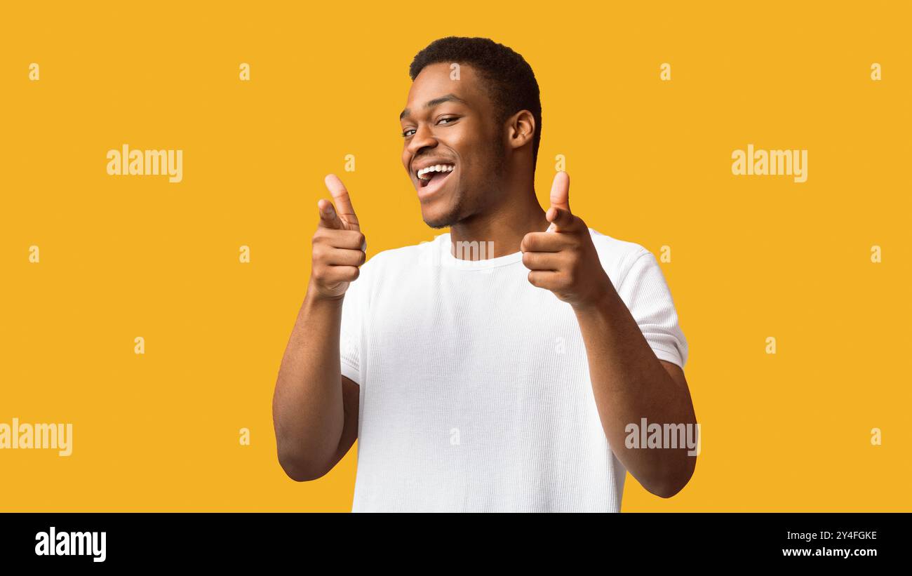 Happy afro guy choosing you over orange background Stock Photo - Alamy