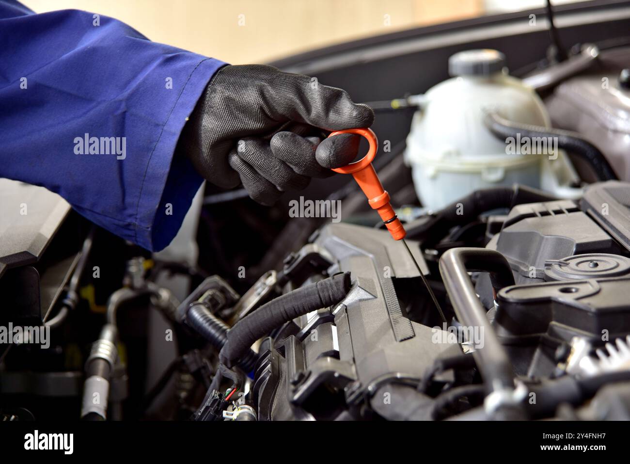 The mechanic pulls out the oil level control rod in the car engine ...