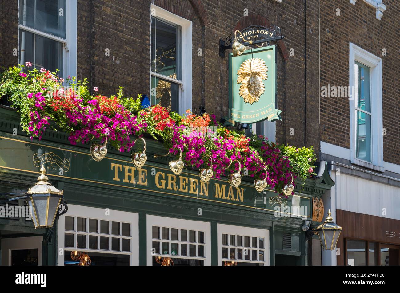 Nicholson’s pub The Green Man pub marquee with hanging sign and floral display in flower boxes ...