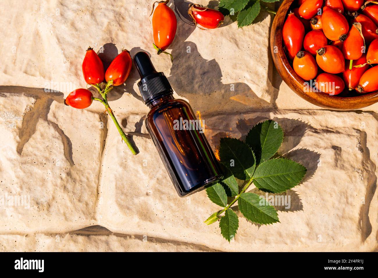 Cosmetic dropper bottle with natural organic rosehip oil on a stone ...