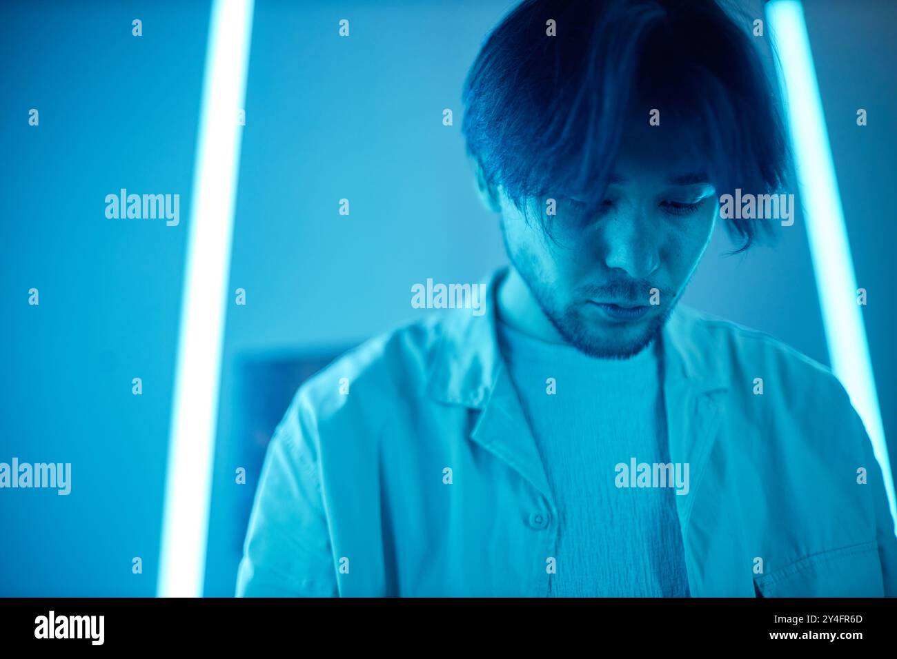 Minimal portrait of adult Asian man in room with blue neon lights ...