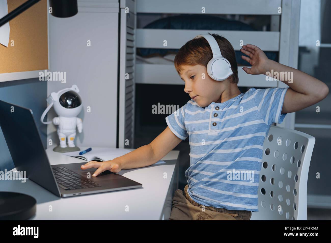 caucasian little boy studying at home sitting at the desk stretching ...