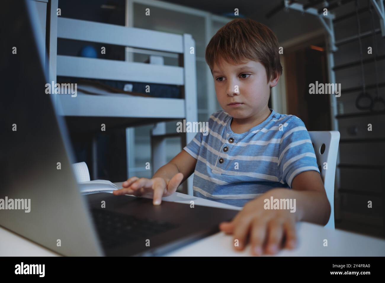 caucasian little boy studying at home typing on laptop. Distant ...