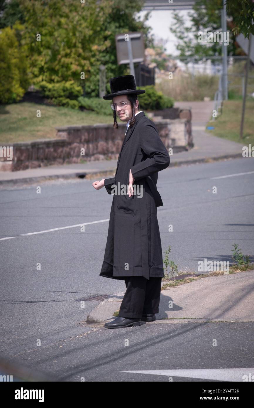 An orthodox young man with long curly peyus sticks his thumb out to ...