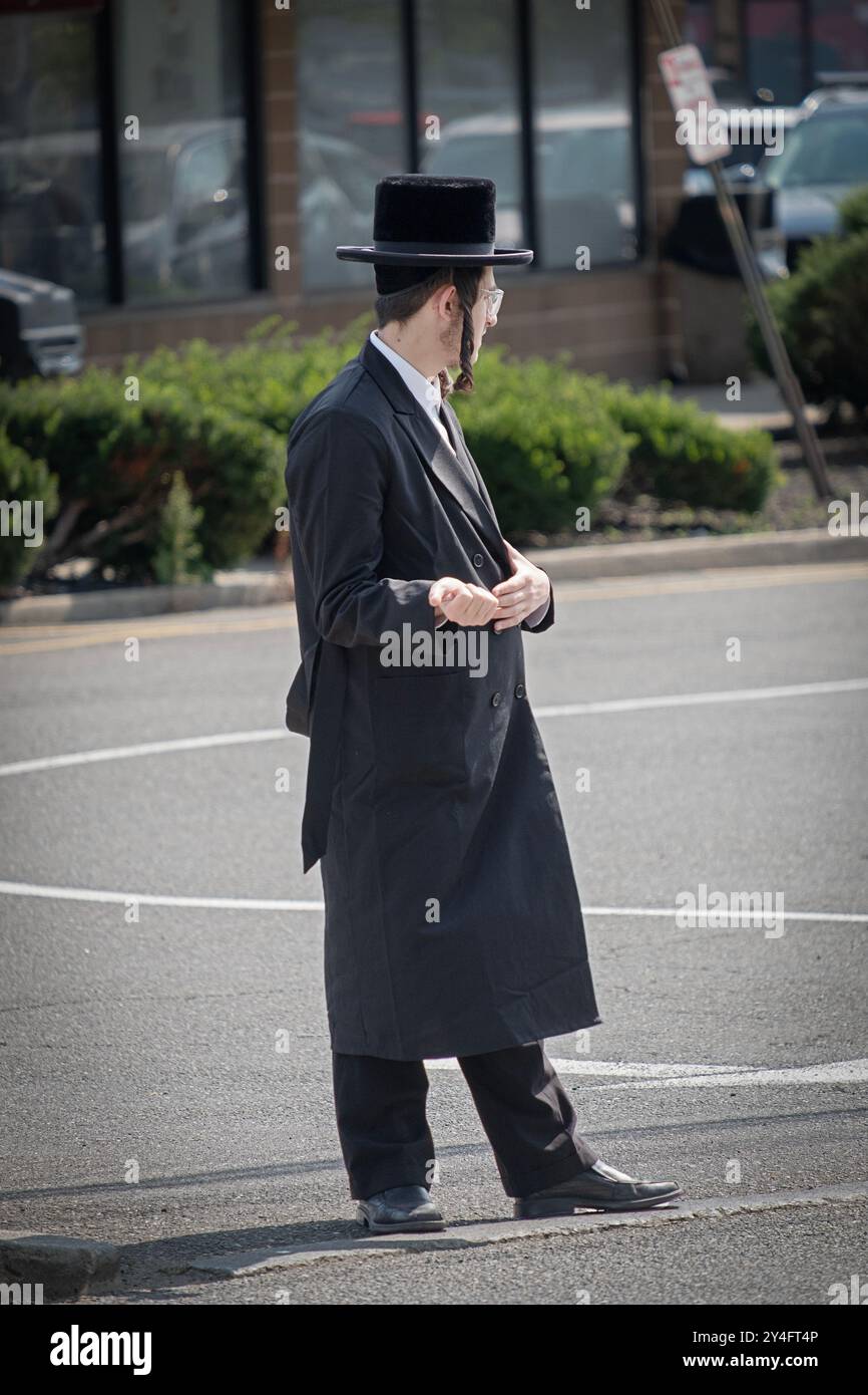 An orthodox young man with long curly peyus sticks his thumb out to ...