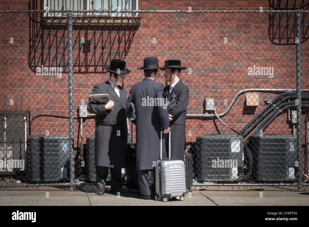 3 orthodox Jewish young men with suitcases wait for a bus after ...