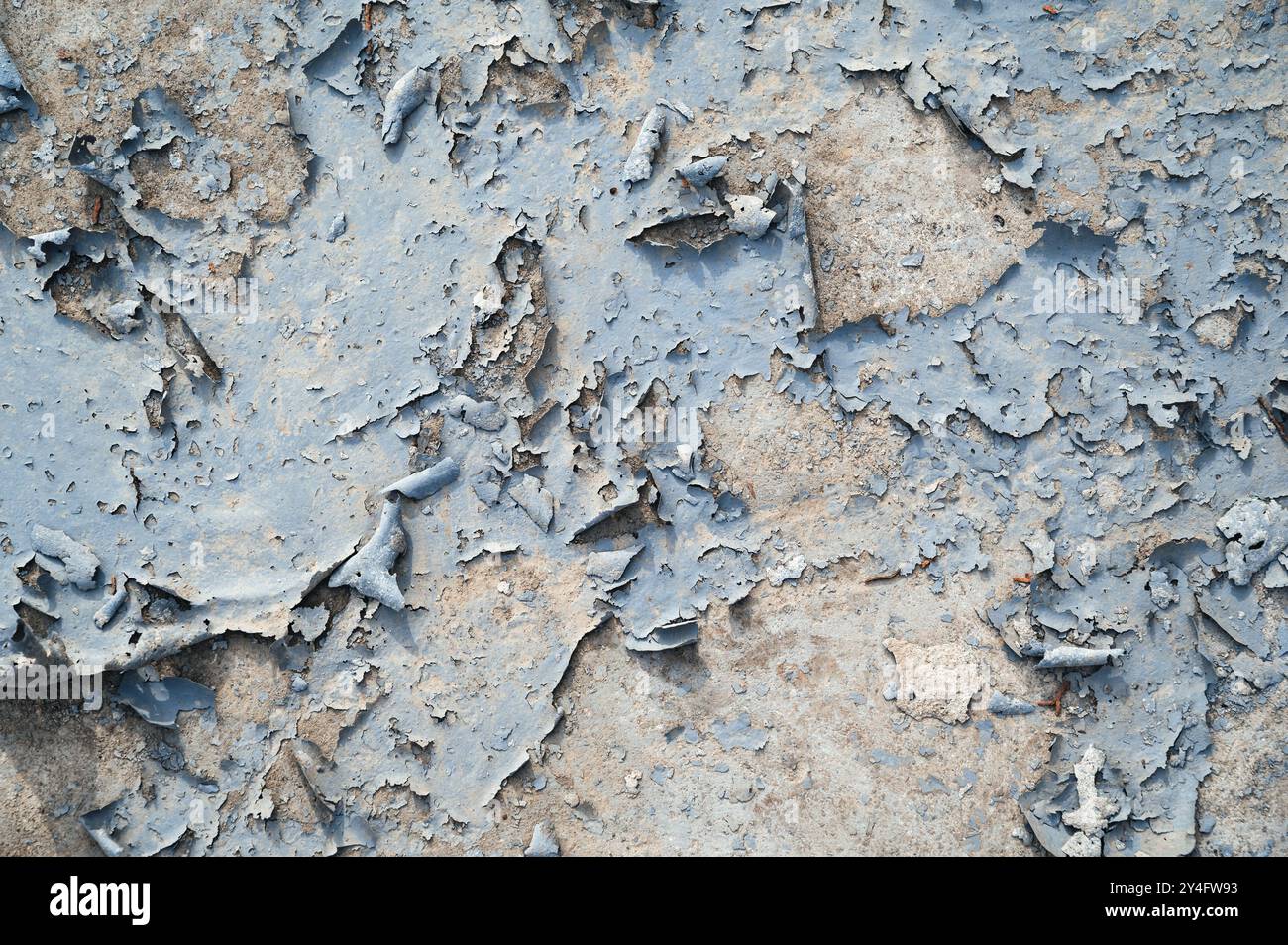 a concrete wall with old cracked flaking paint. Weathered rough painted surface with patterns of ...