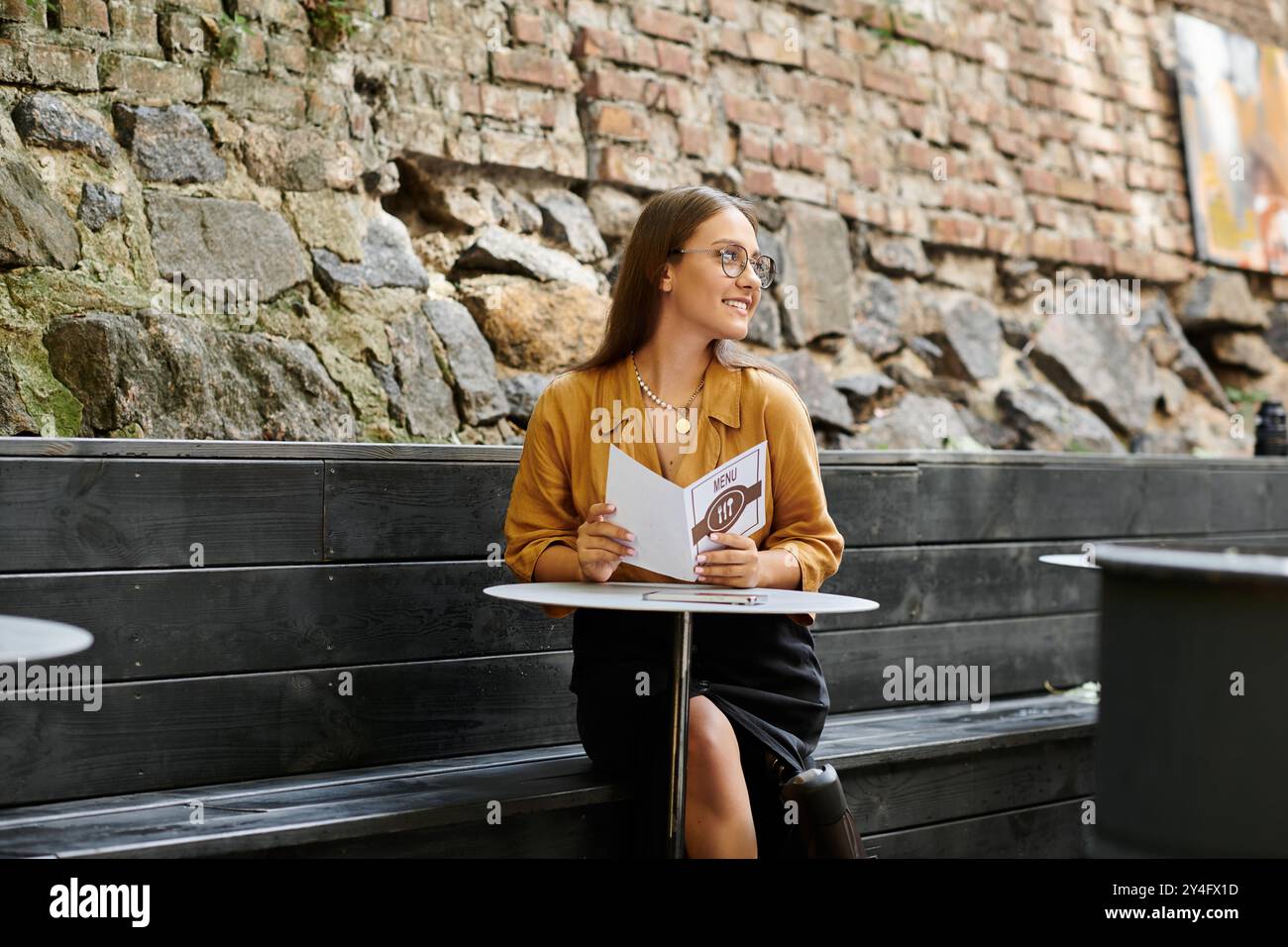 In a stylish cafe, a young woman with a prosthetic leg sits comfortably ...