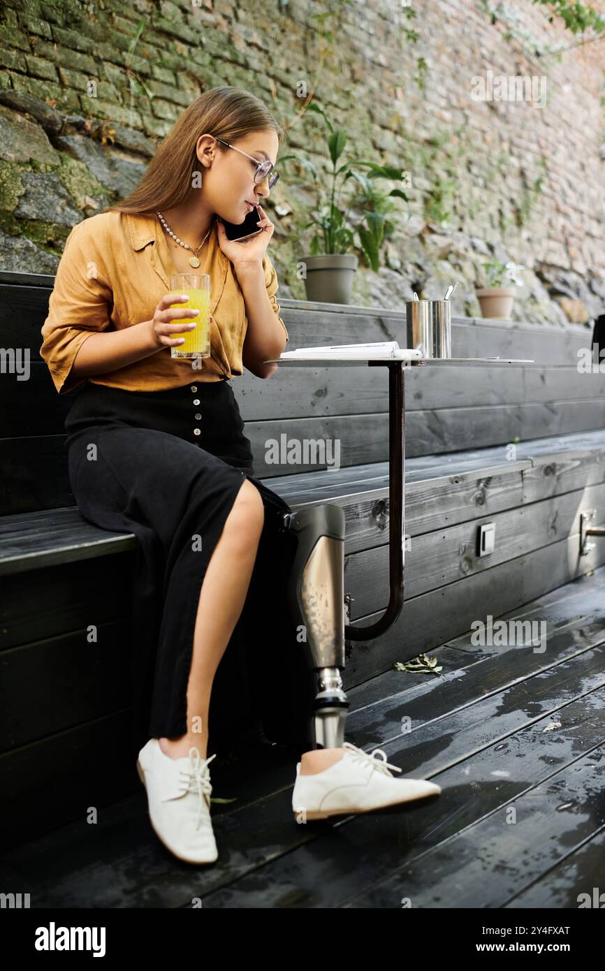 A young woman sips a drink while talking on the phone, comfortably ...