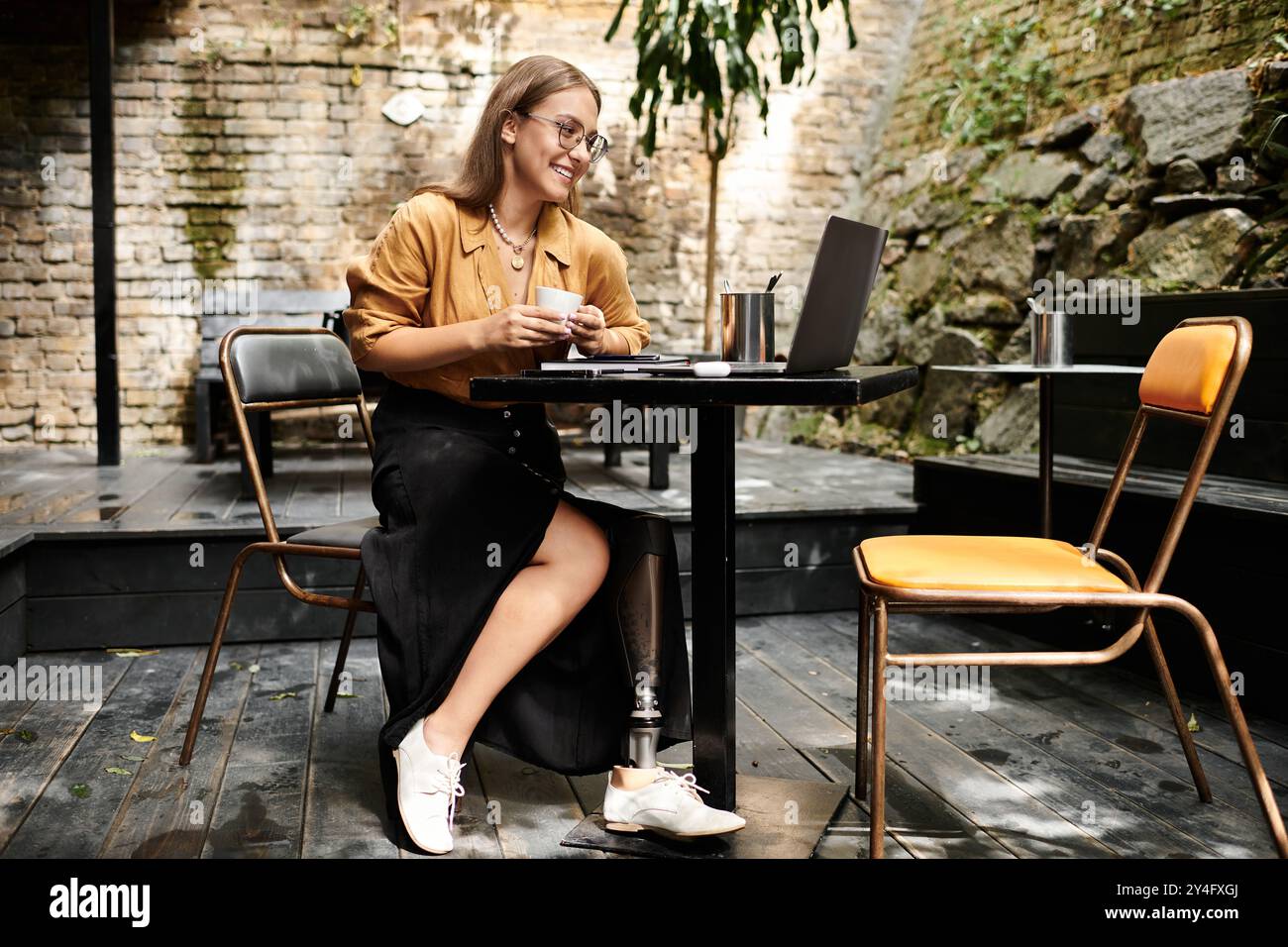 A young woman with an artificial limb sits comfortably in a cafe ...
