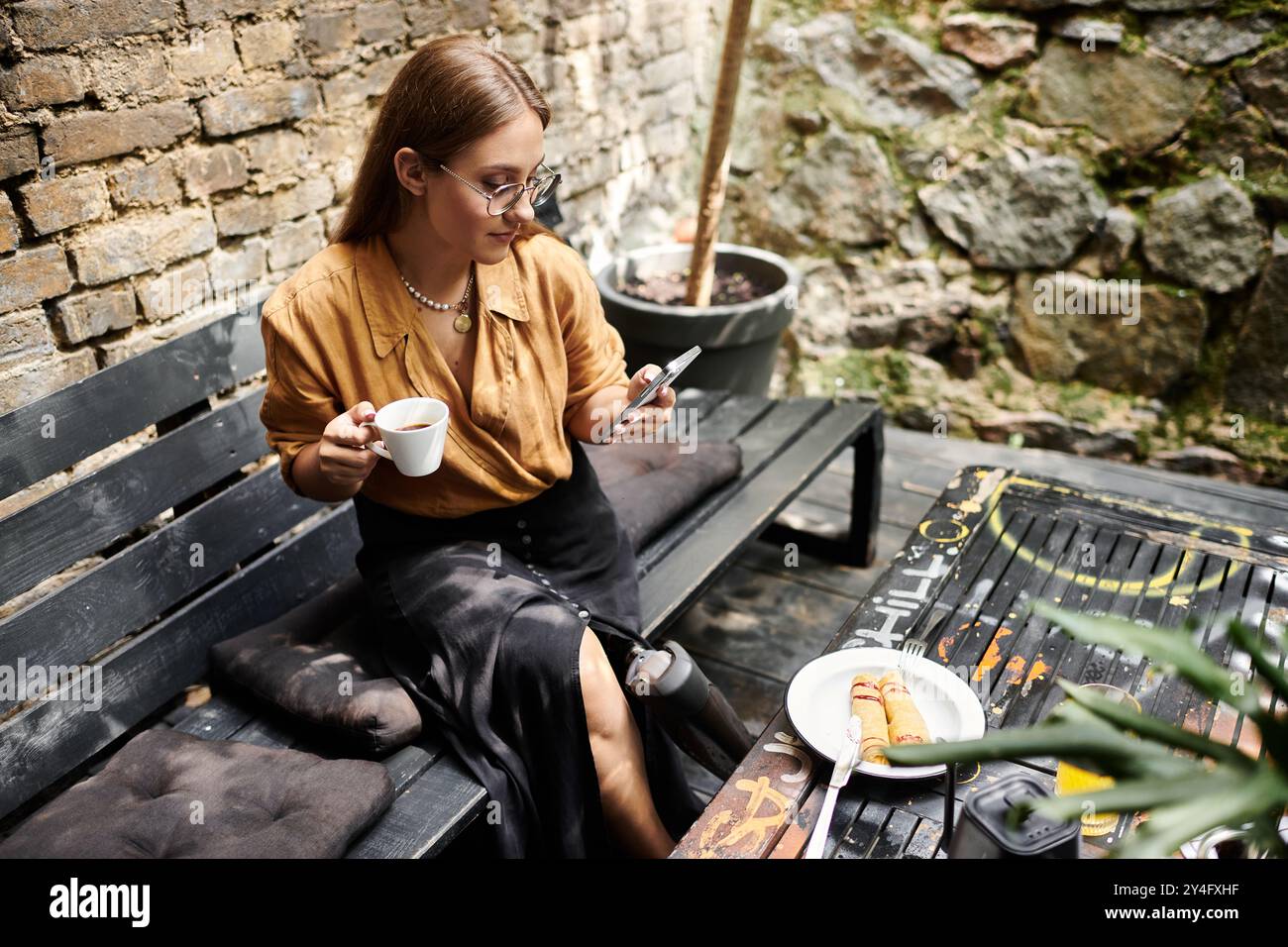 A young woman relaxes in a cafe, sipping coffee and using her phone ...