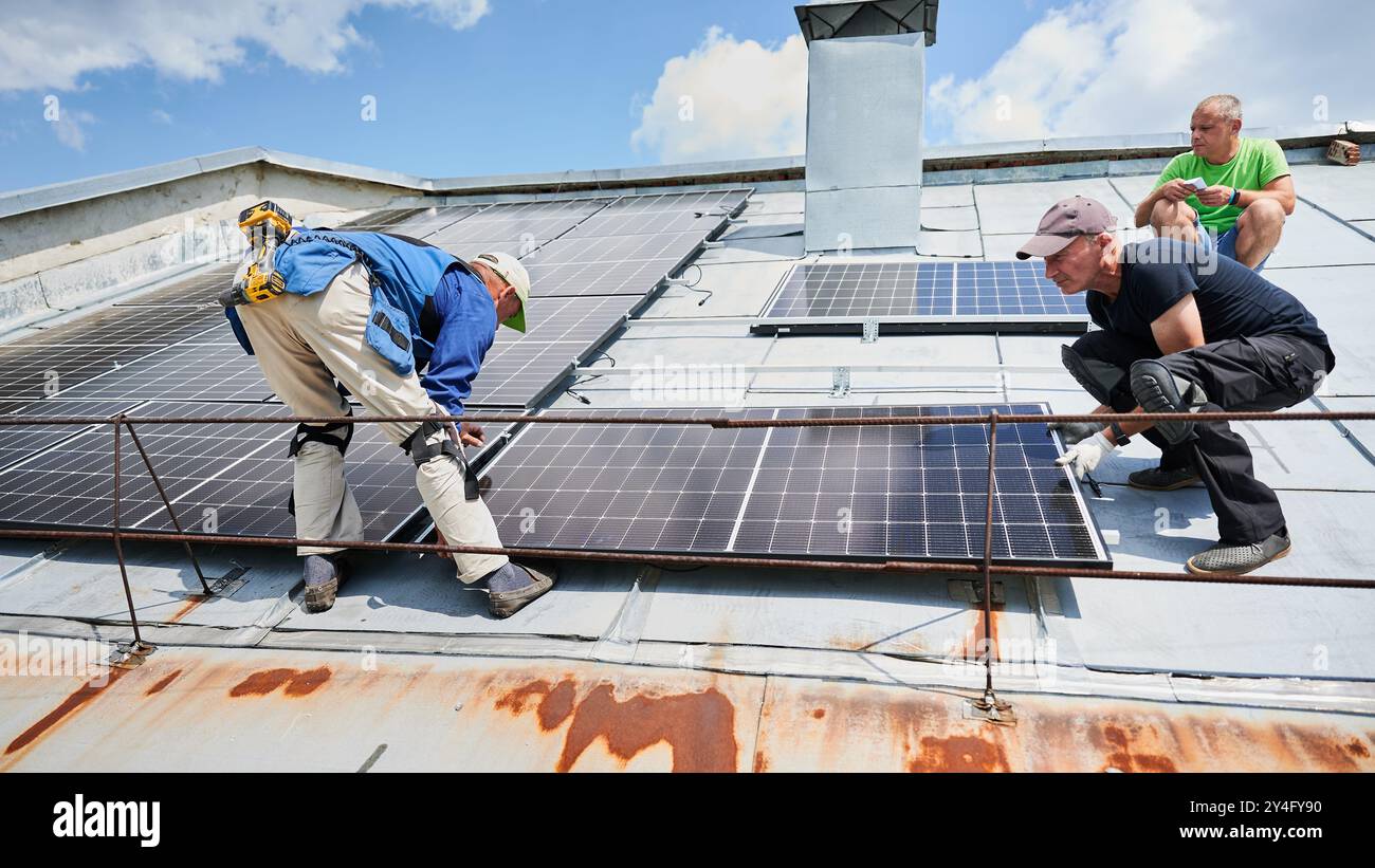 Workers building solar panel system on metal rooftop of house. Three ...