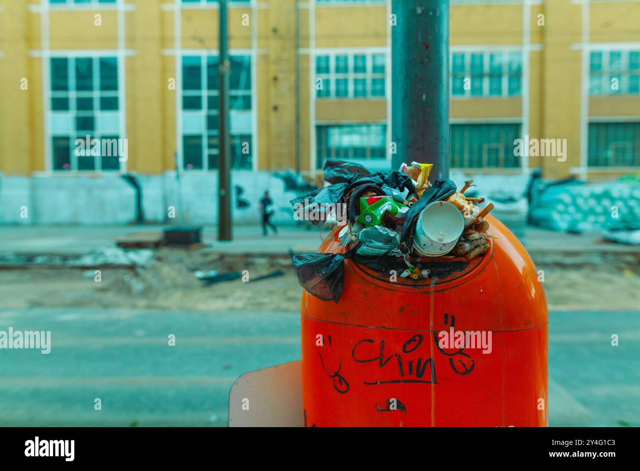 An overfilled trash can with a lot of garbage sticking out of the ...