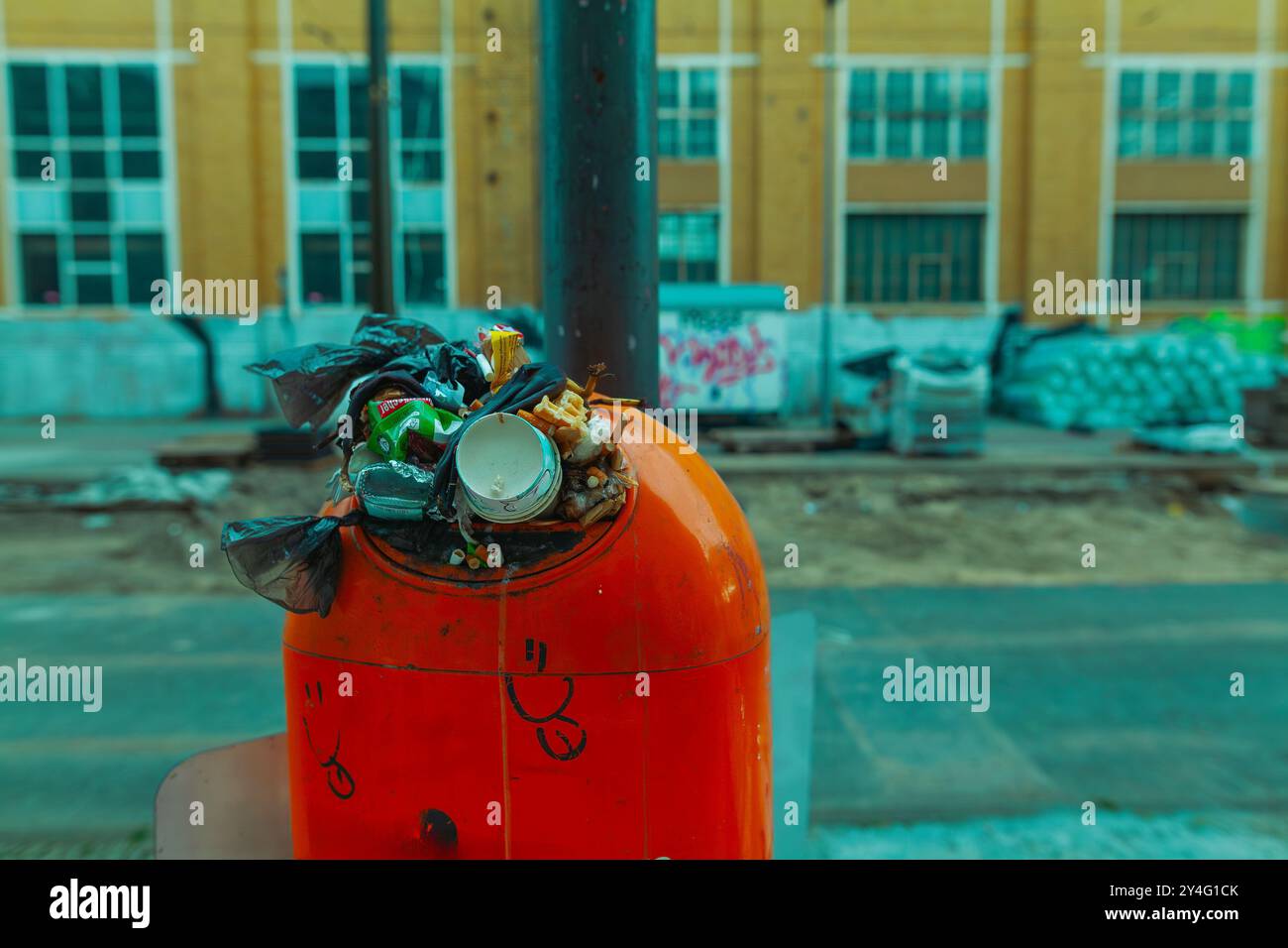 An overfilled trash can with a lot of garbage sticking out of the ...