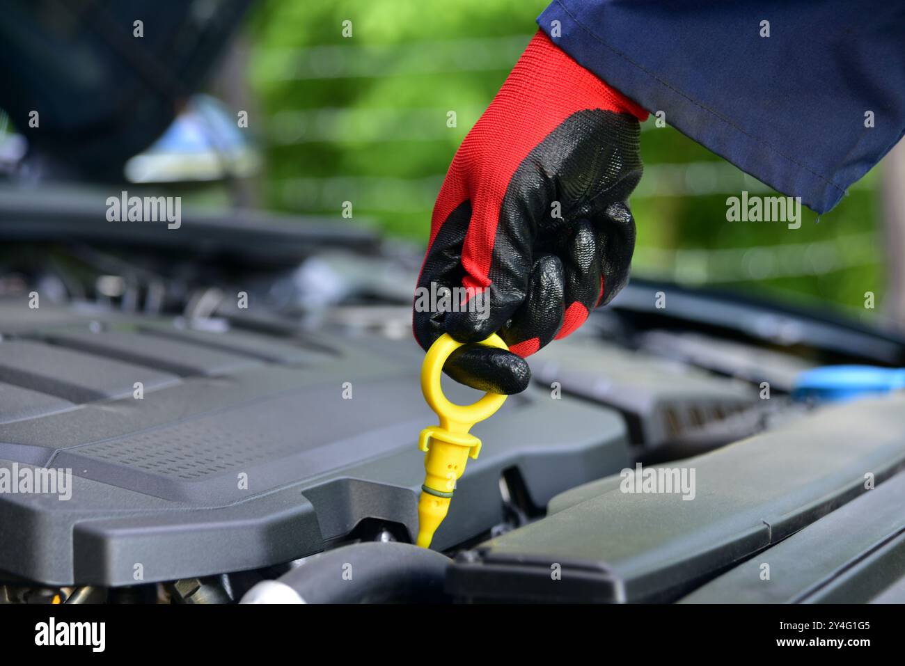 hecking the amount of oil in the car engine via the level control rod ...