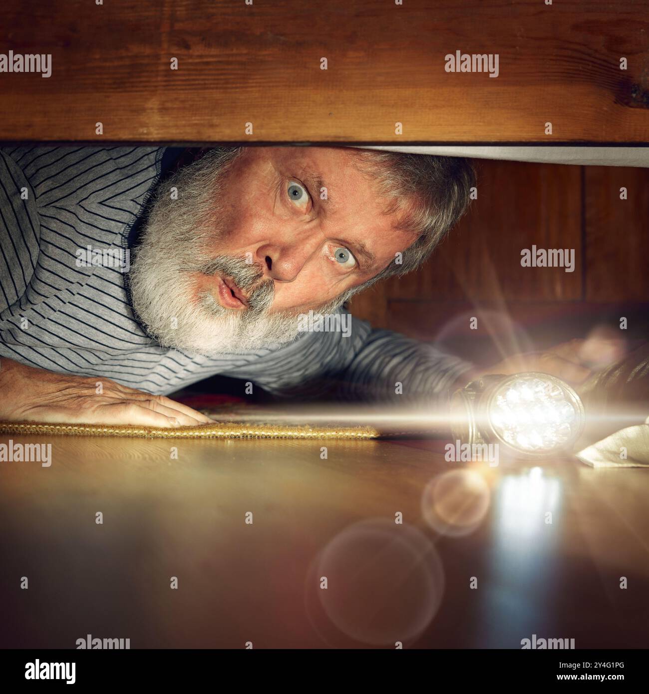 Older man peeking out from under bed, with eyes wide in surprise ...