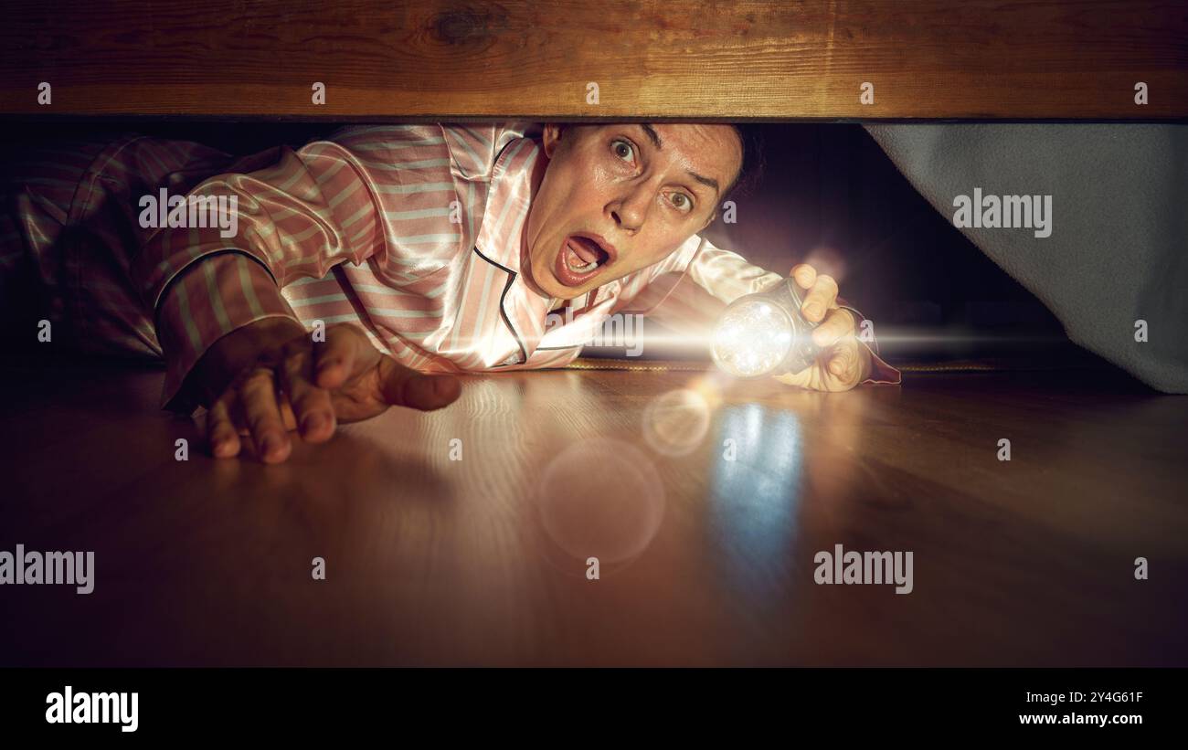 Senior woman with emotional face, lying on floor and looking under bed ...