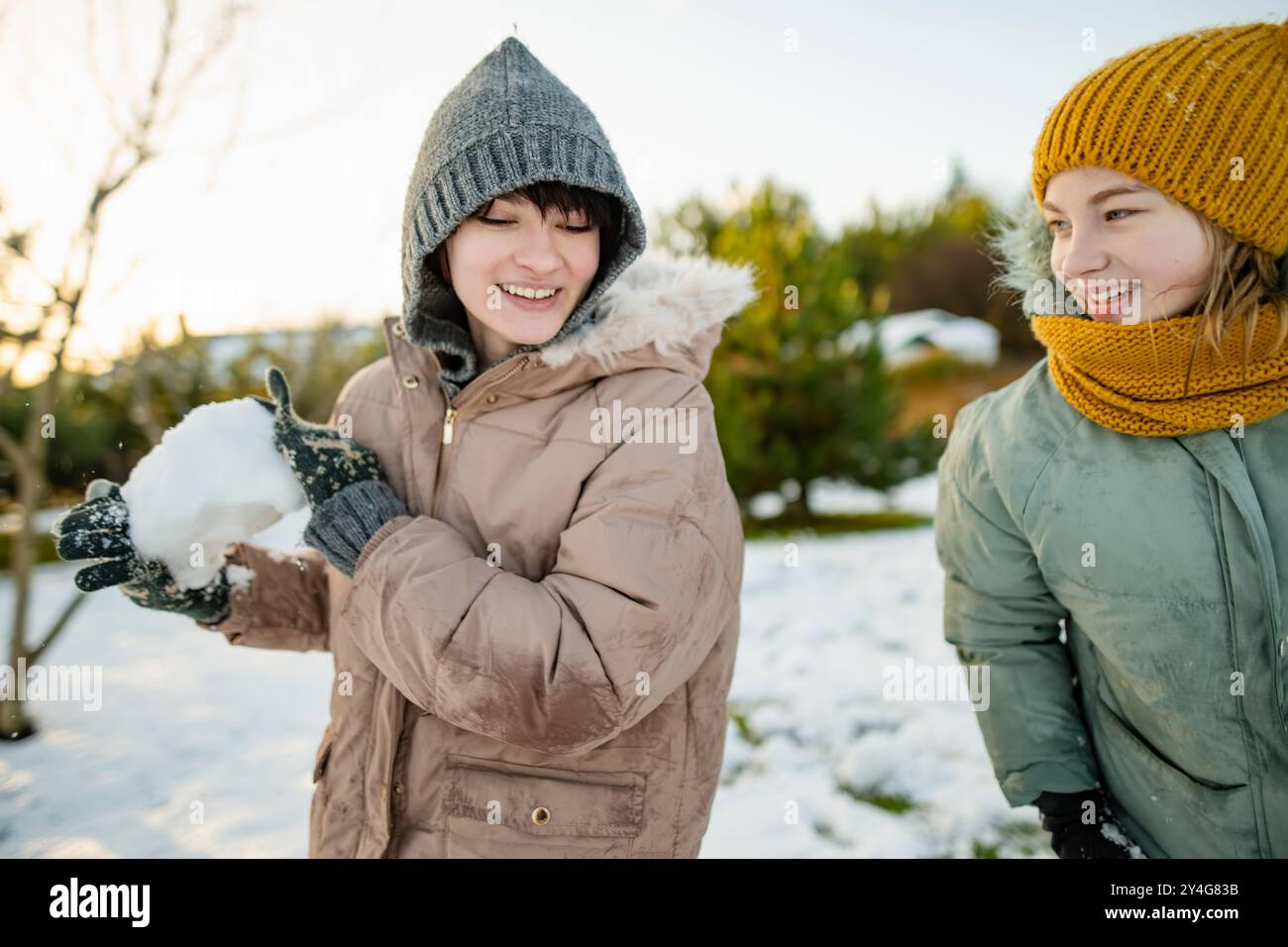 Adorable teenage girls building a snowman in the backyard. Cute ...