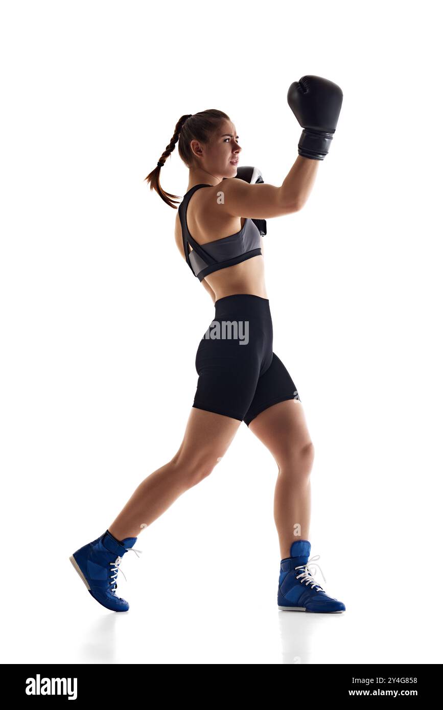 Uppercut punch. Full-length image of focused young girl, boxing athlete ...