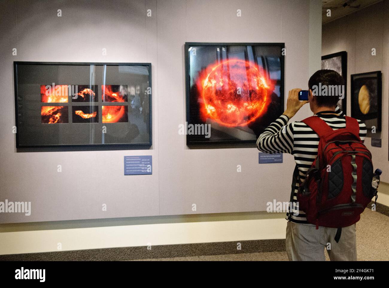 A visitor takes a photo of images of the sun at Michael Benson's ...