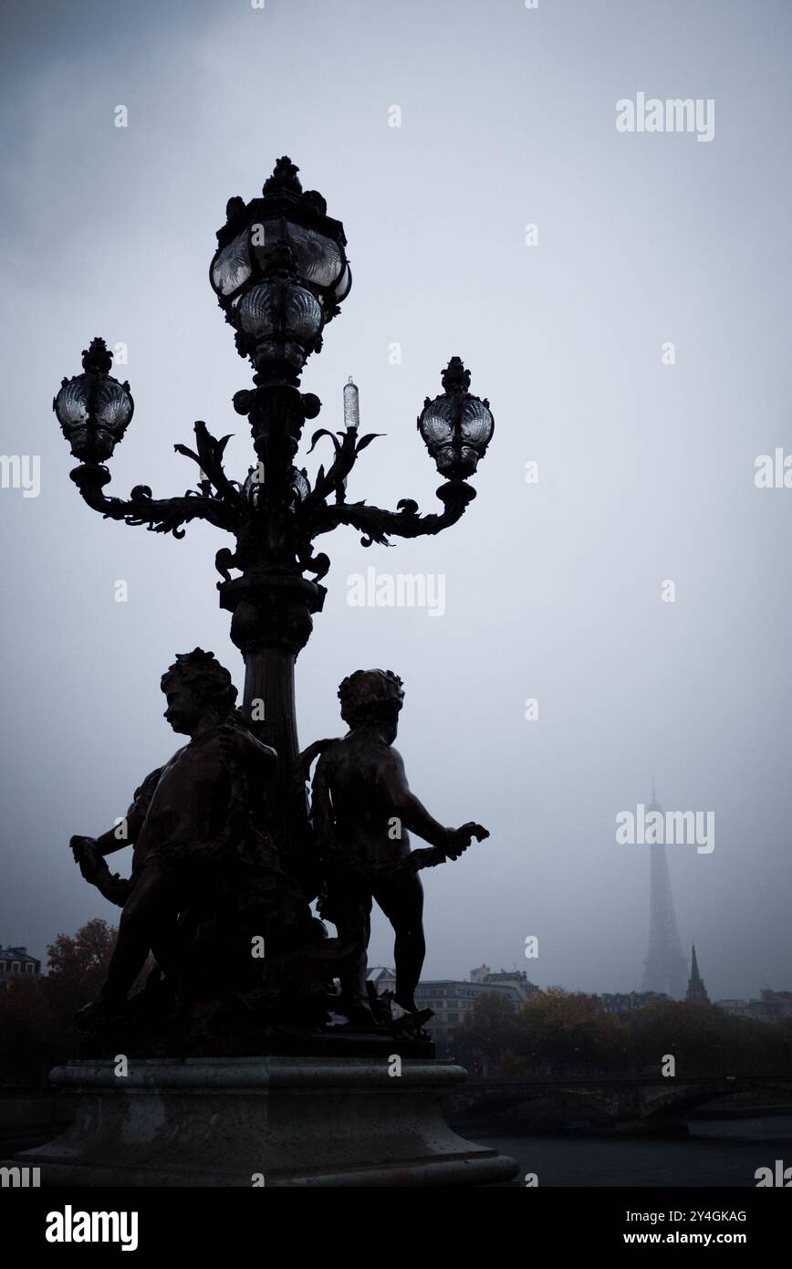 An ornate lamp post with statues is silhouetted on a very rainy and ...