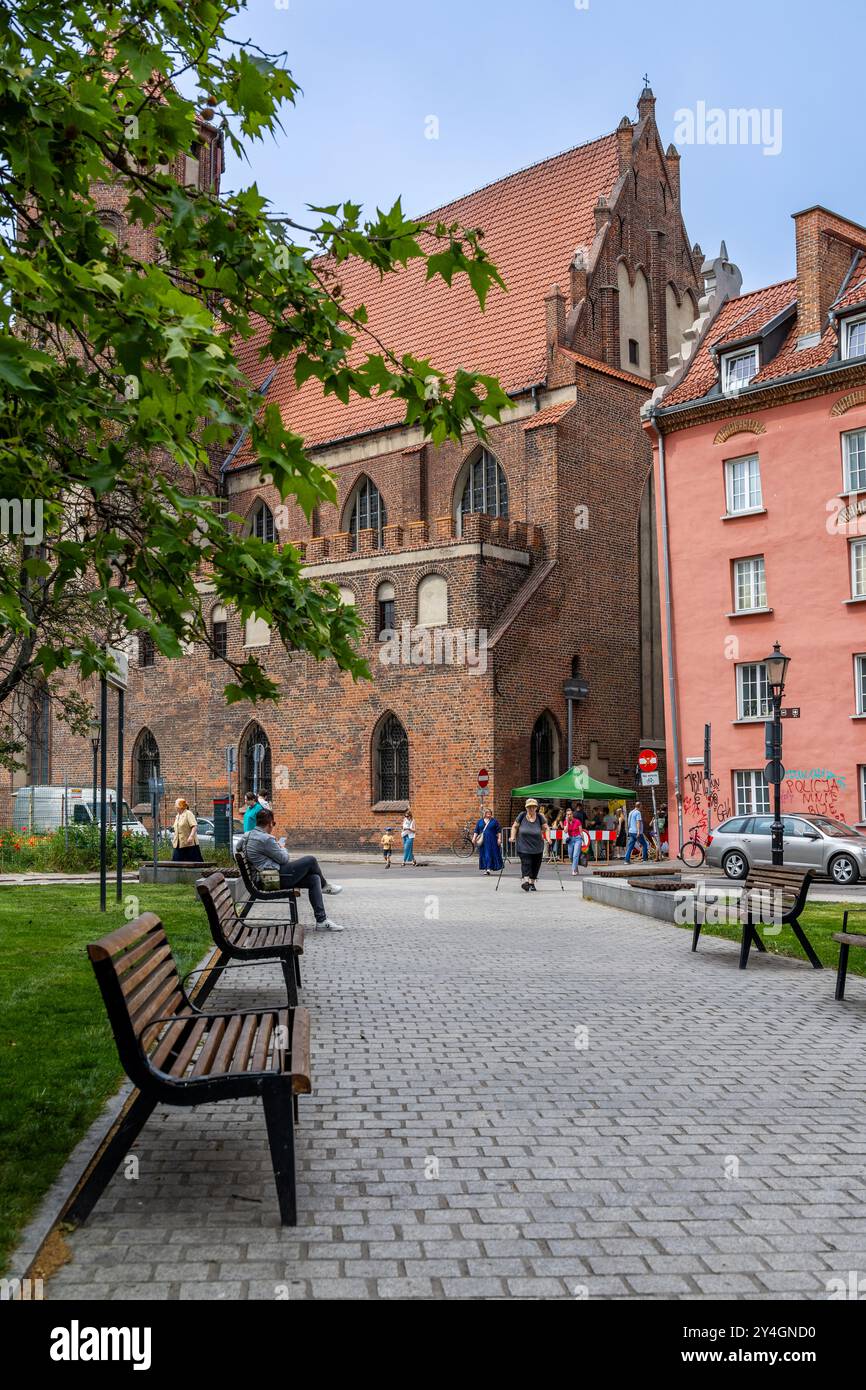 People enjoying a quiet park with benches near a historic red brick ...