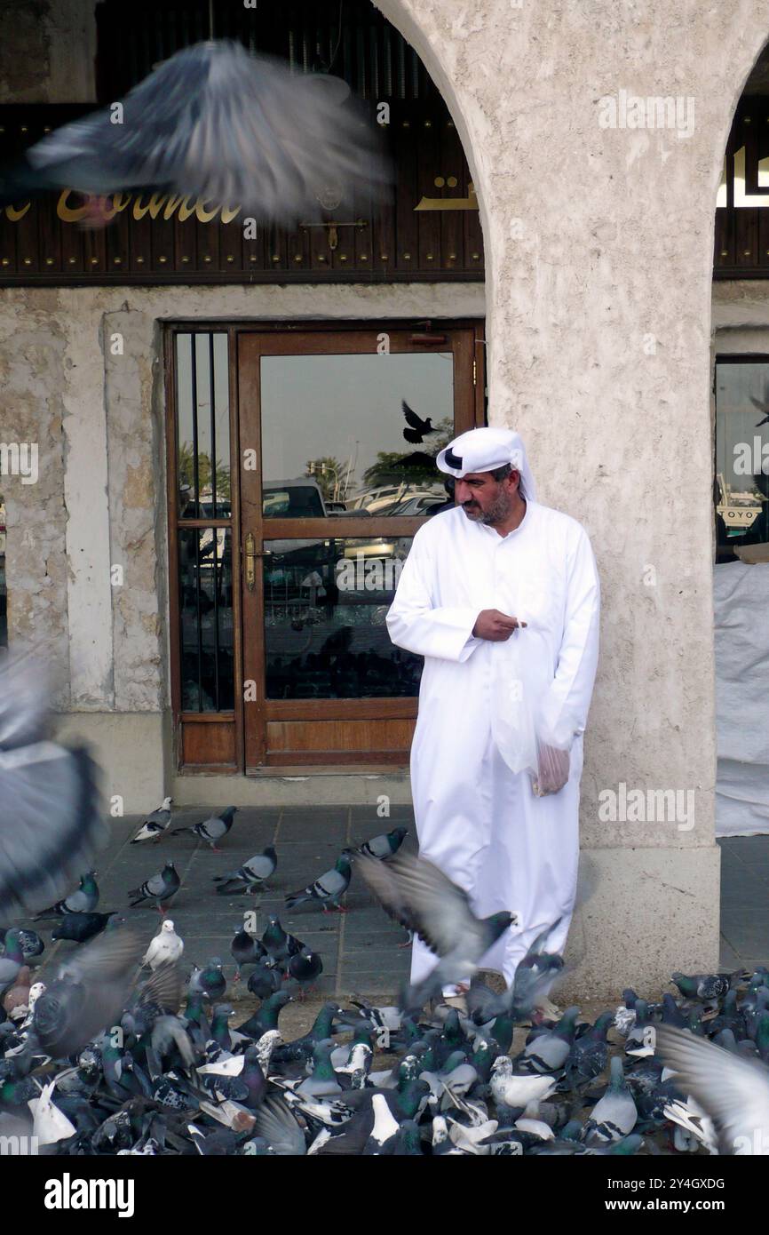 Man in typical Arab clothing feeding pigeons, Doha (Qatar Stock Photo ...