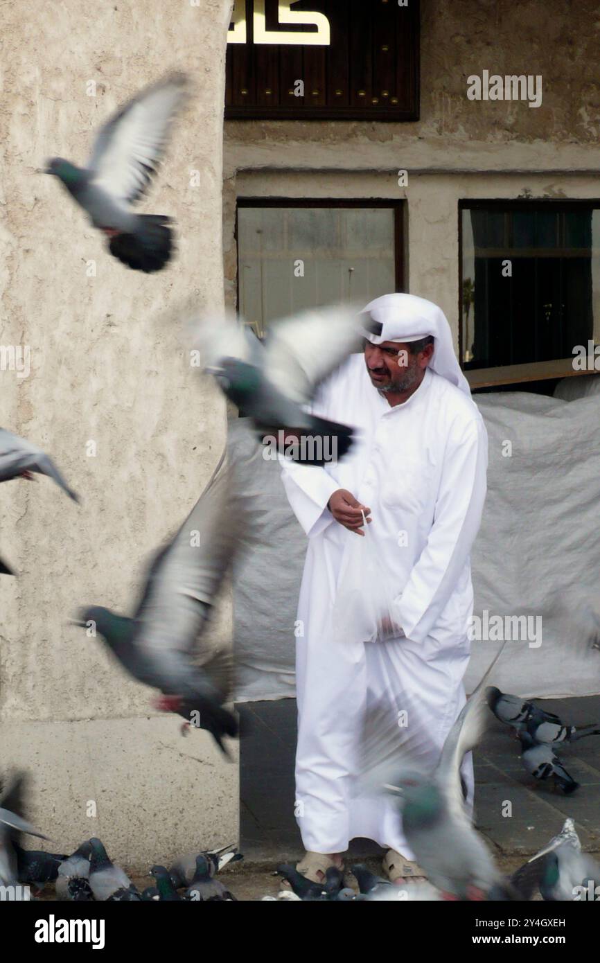 Man in typical Arab clothing feeding pigeons, Doha (Qatar Stock Photo ...