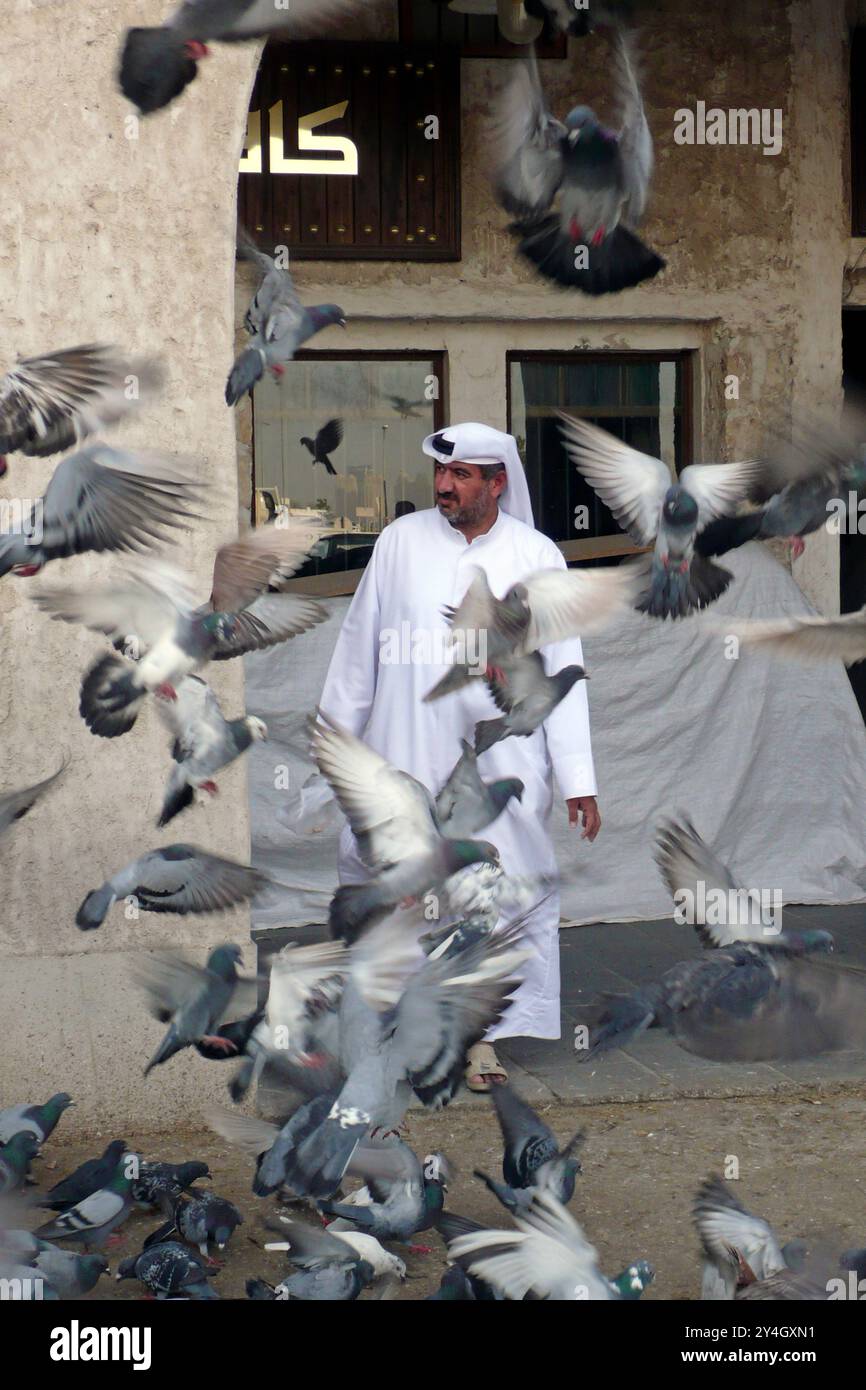 Man in typical Arab clothing feeding pigeons, Doha (Qatar Stock Photo ...