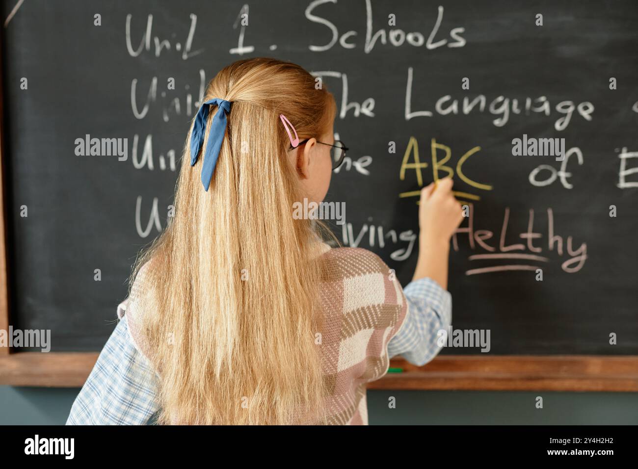 Back view of young girl with long blonde hair decorated with ribbon ...