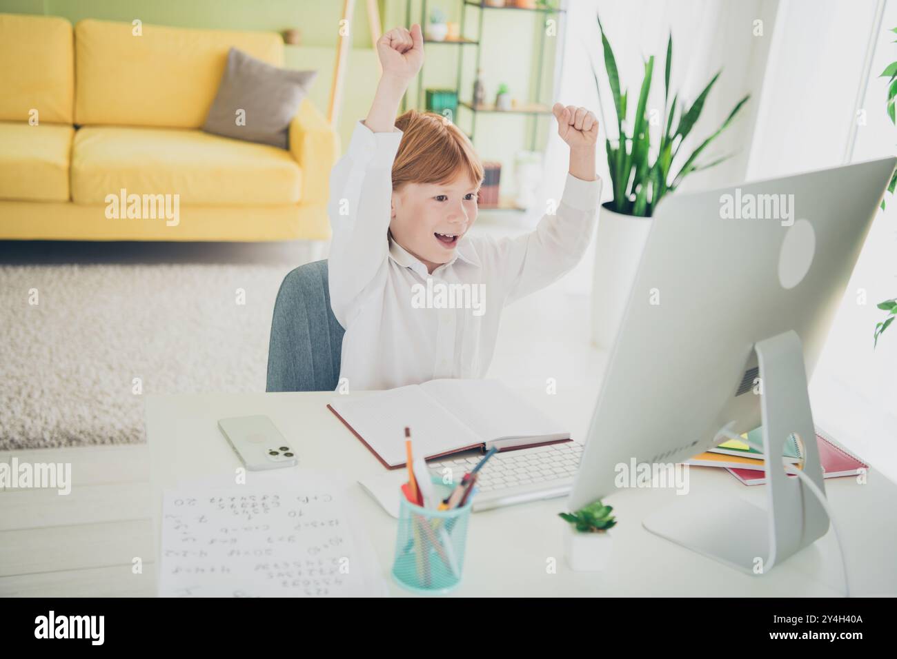 Portrait of positive glad cheerful learner boy sitting chair desk use ...