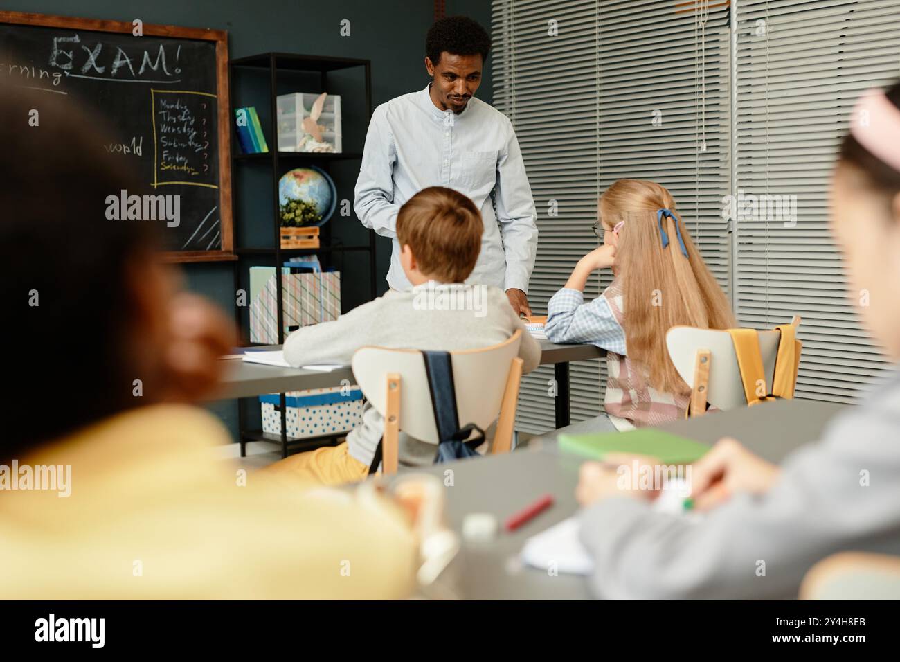 Supportive African American male teacher talking to young students ...