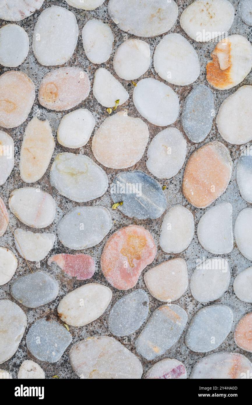 A detailed close-up of a white pebble path lined with stone. Vertical ...